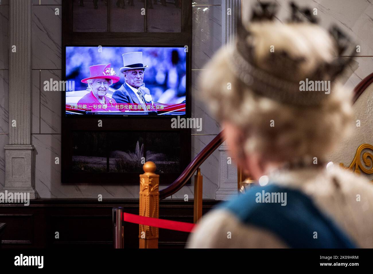 Photographs on TV in front of a wax figure of the late Britain's Queen ...