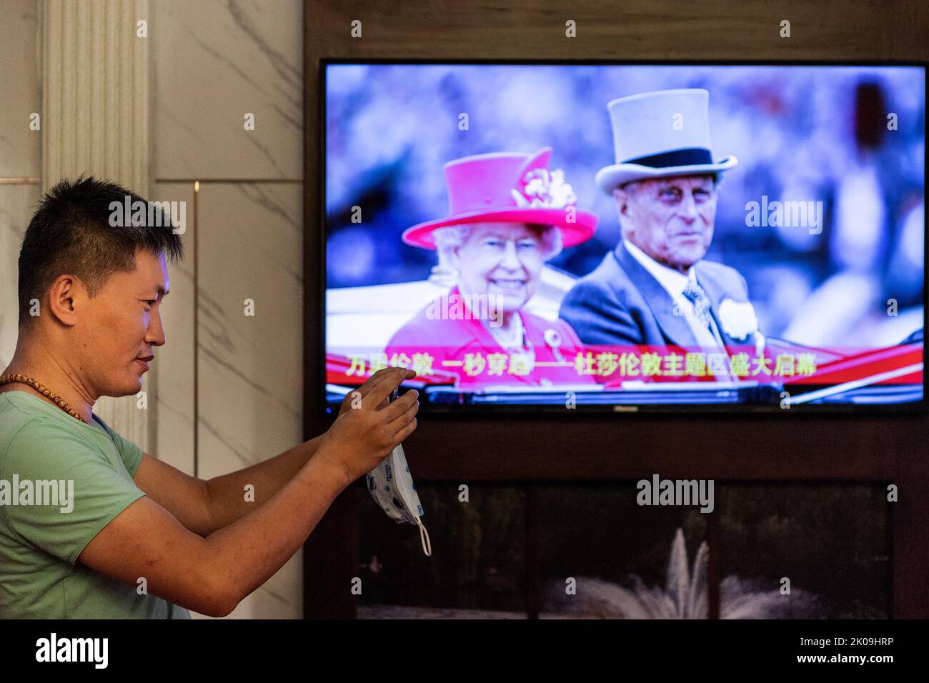 A man takes photo next to photographs of Britain's Queen Elizabeth II ...