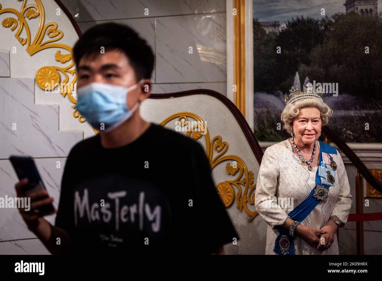 A man stands in front of a wax figure of Britain's Queen Elizabeth II ...
