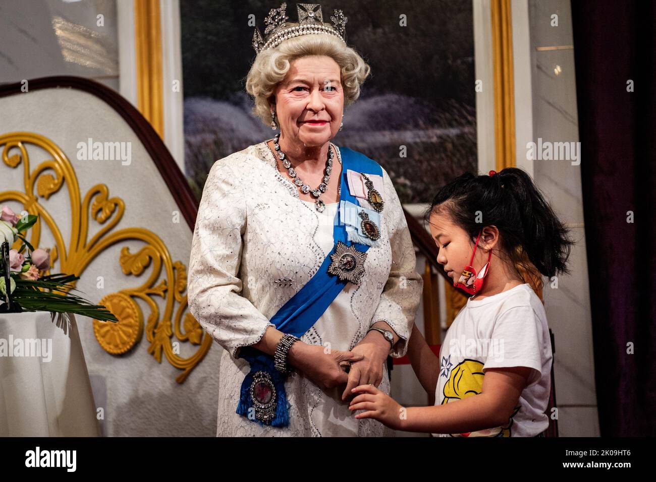 A girl touches a wax sculpture of Queen Elizabeth II at Wuhan Madame ...
