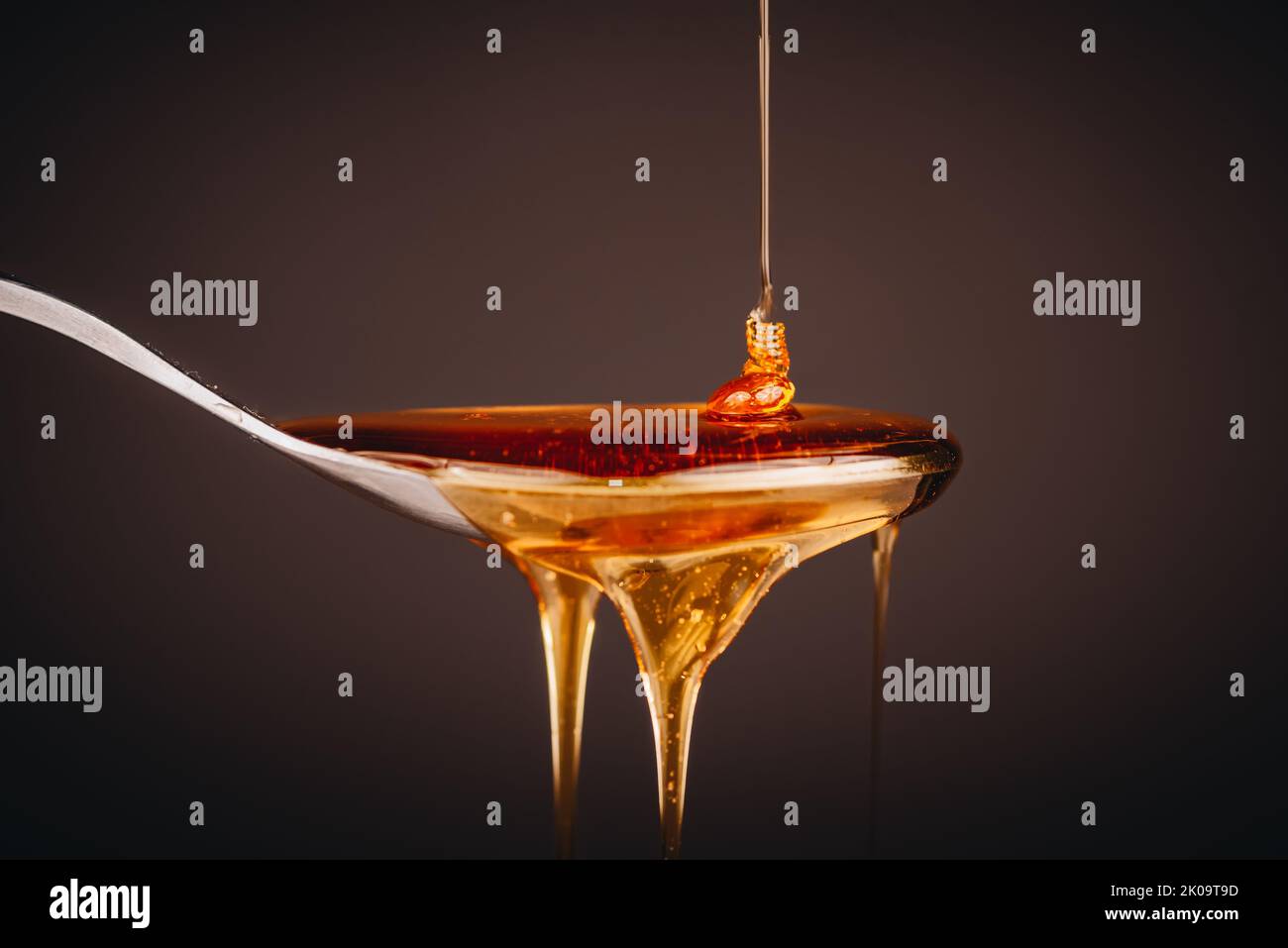 close up of honey being poured into a silver spoon, honey is a natural ...