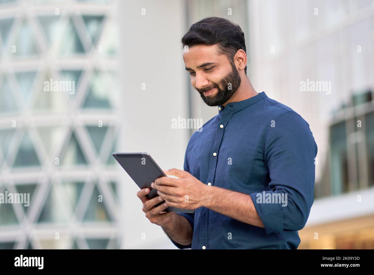 Smiling indian professional business man using digital tablet outdoors ...