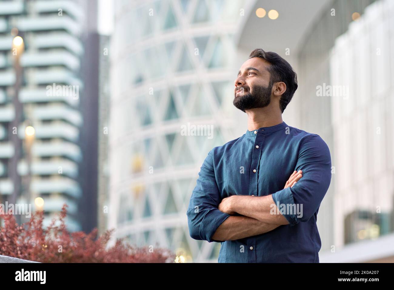 Confident rich indian business man standing in city dreaming of success ...