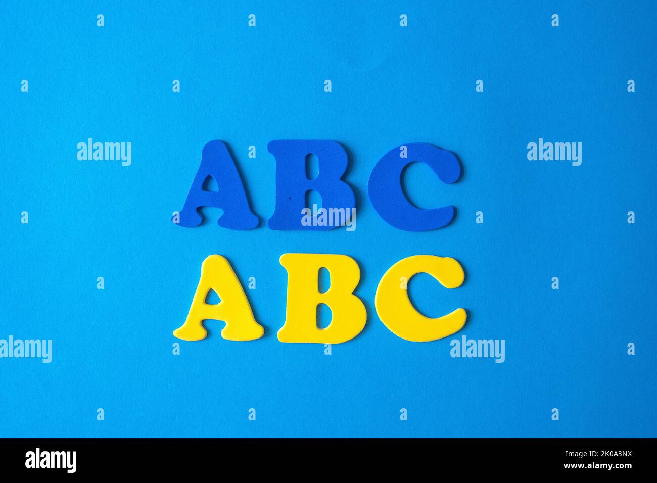 Blue and yellow letters of the alphabet on a blue background. The ...
