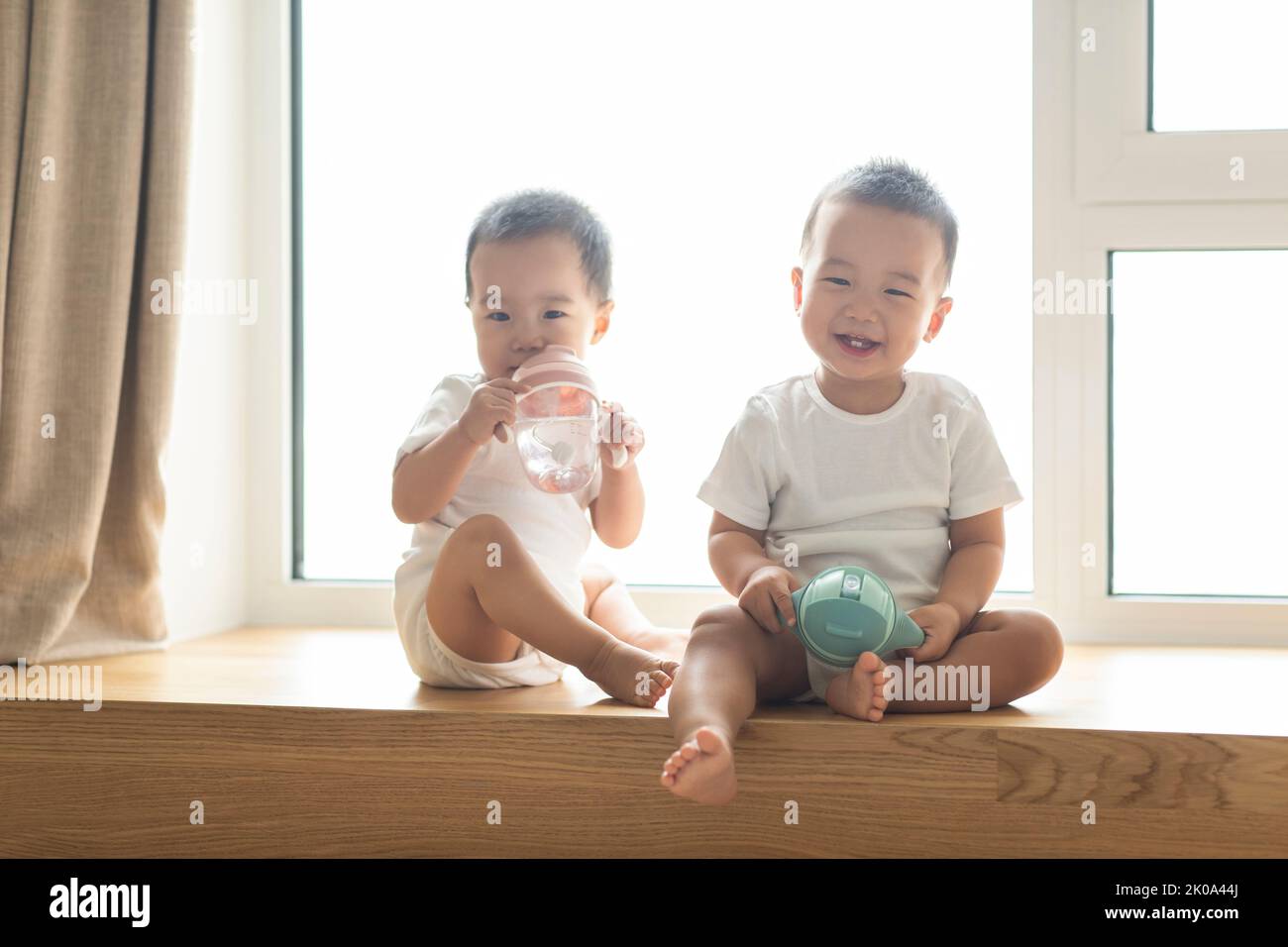 Cute Chinese twin babies drinking water from baby bottles Stock Photo ...