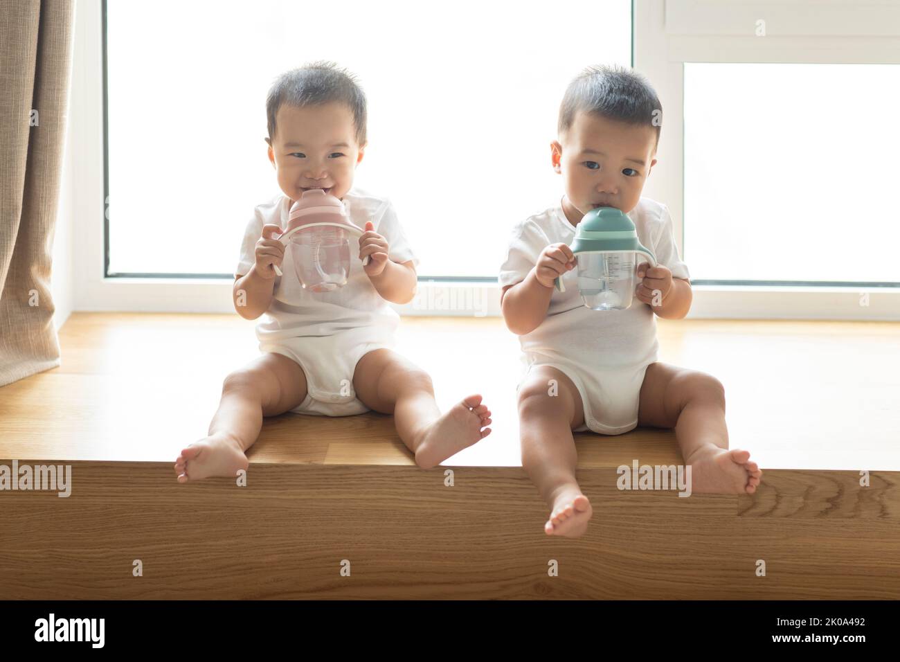 Cute Chinese twin babies drinking water from baby bottles Stock Photo ...