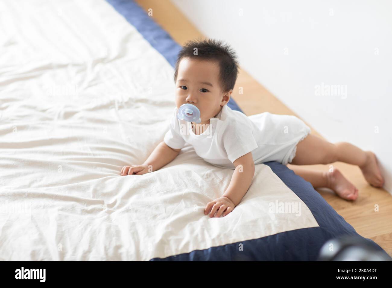 Cute Chinese baby lying on bed with pacifier Stock Photo - Alamy