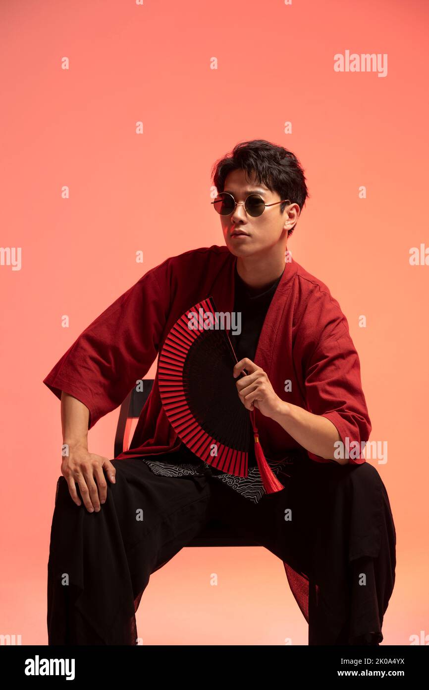 Confident young Chinese man holding a fan Stock Photo - Alamy