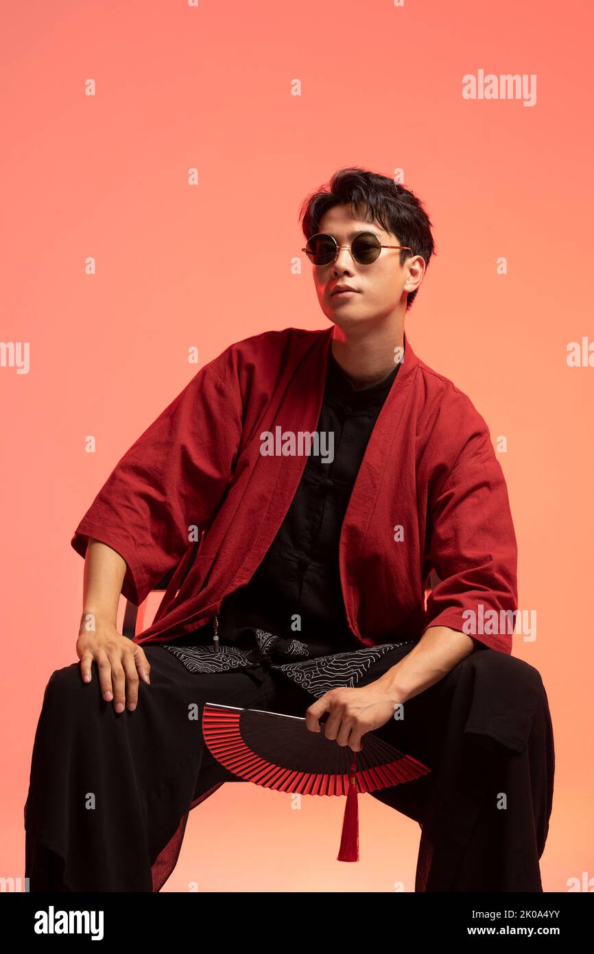 Confident young Chinese man holding a fan Stock Photo - Alamy