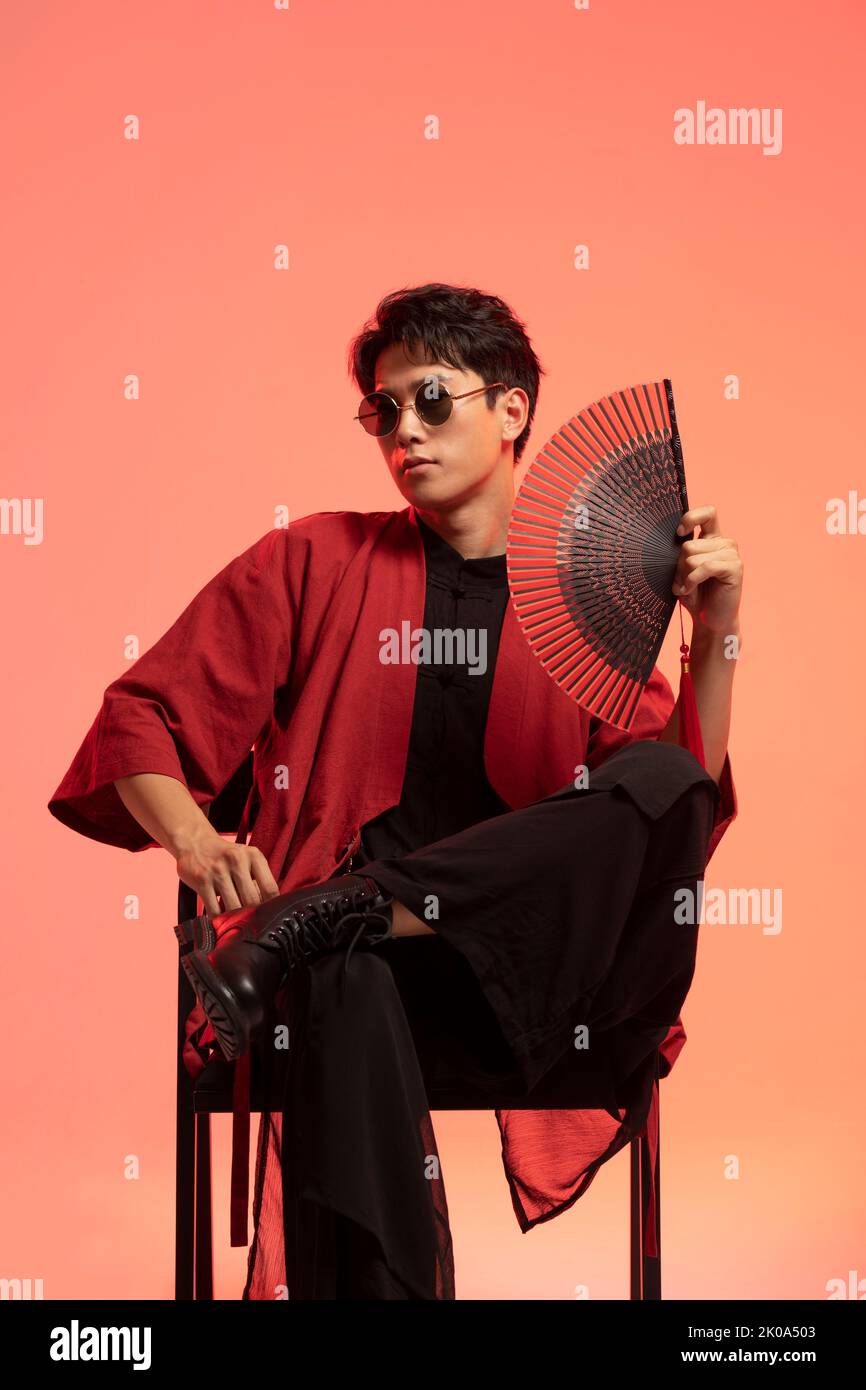 Confident young Chinese man holding a fan Stock Photo - Alamy