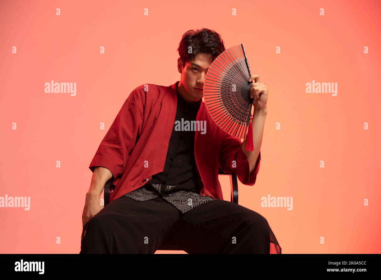Confident young Chinese man holding a fan Stock Photo - Alamy