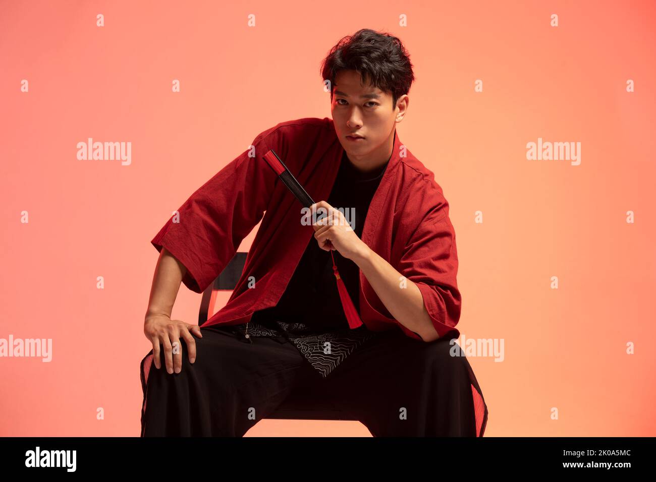 Confident young Chinese man holding a fan Stock Photo - Alamy