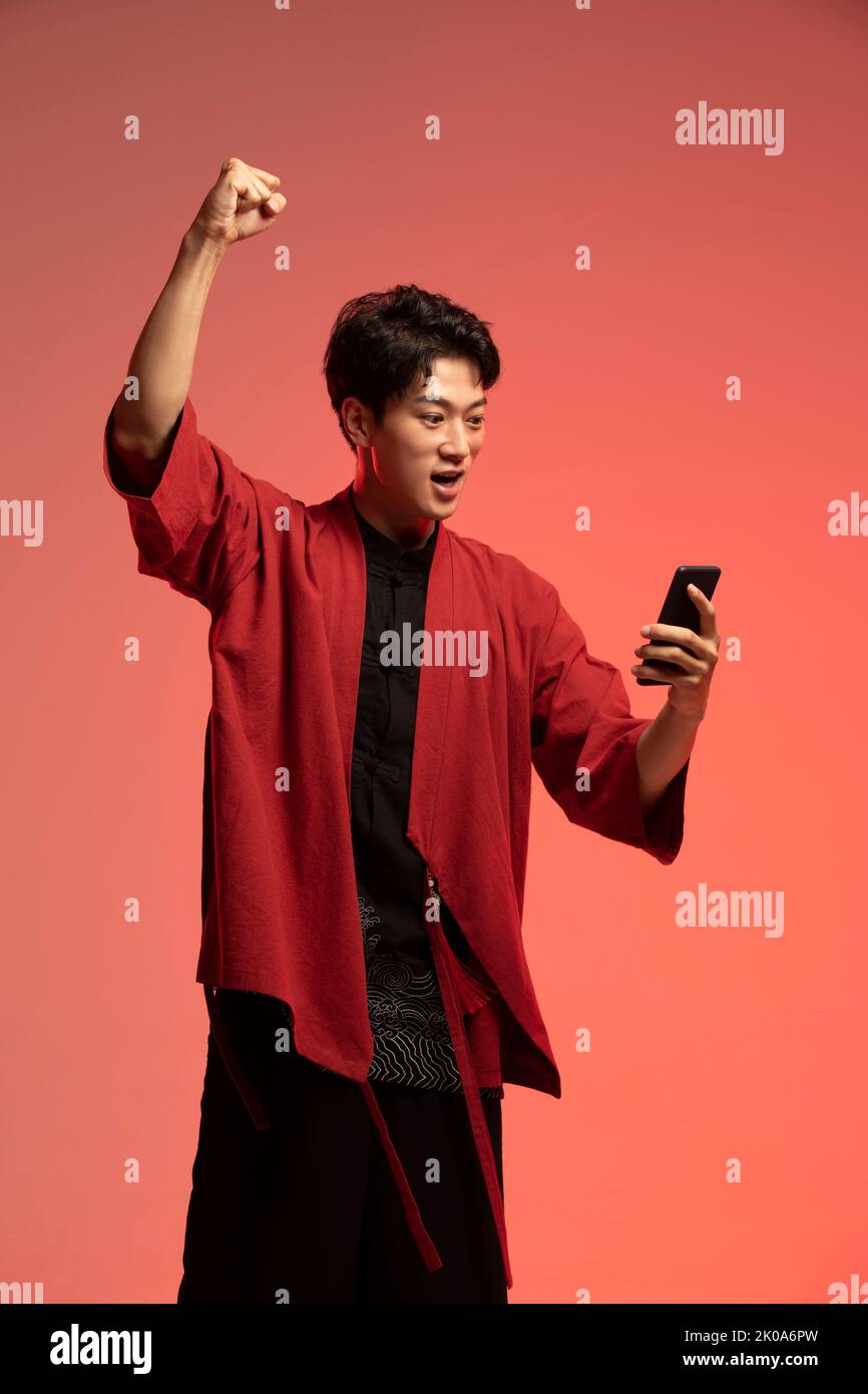 Cheerful young Chinese man holding a smartphone Stock Photo - Alamy