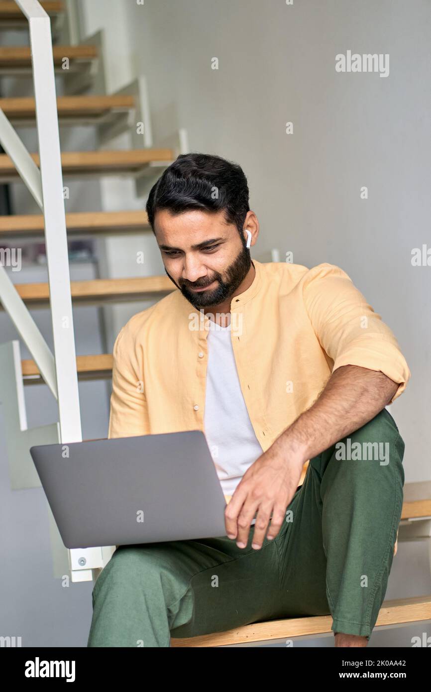 Indian man user sitting at home using laptop remote working, vertical ...