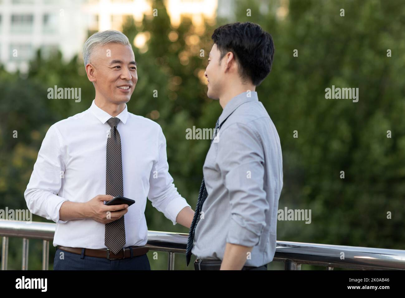 Confident Chinese businessmen talking outdoors Stock Photo - Alamy