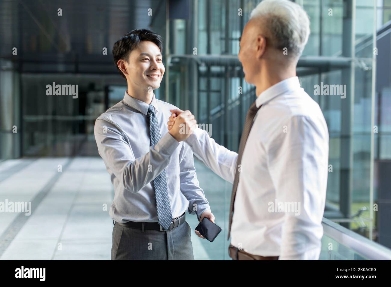 Cheerful Chinese business partners holding hands Stock Photo - Alamy
