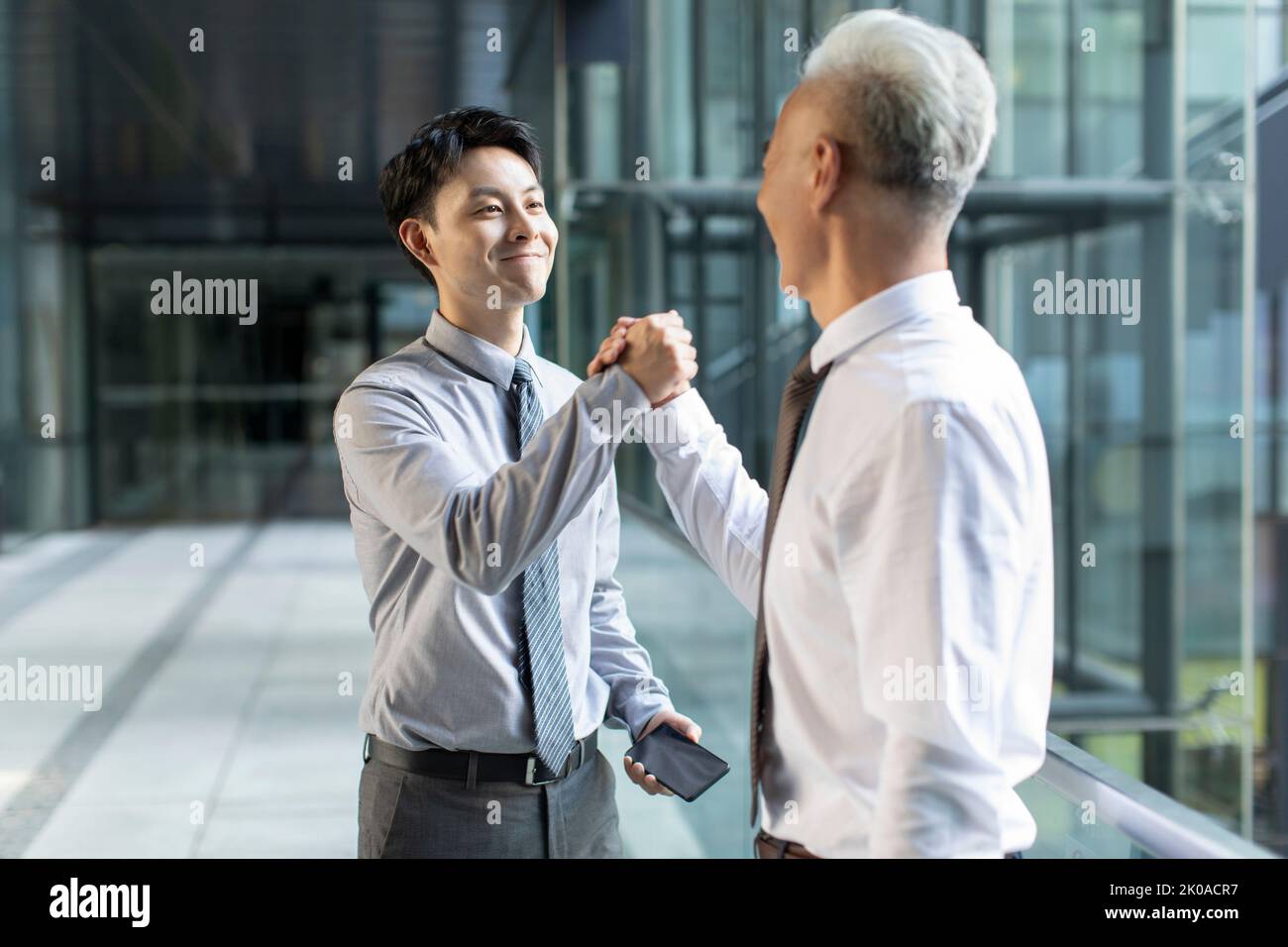 Cheerful Chinese business partners holding hands Stock Photo - Alamy