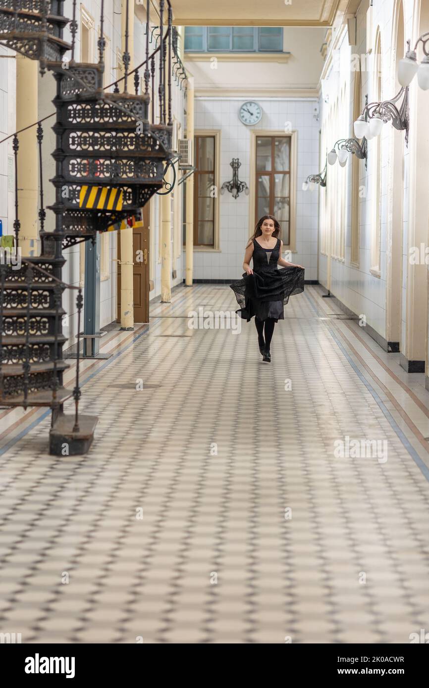 Beautiful girl in black dress running in hall checkered floor. High ...