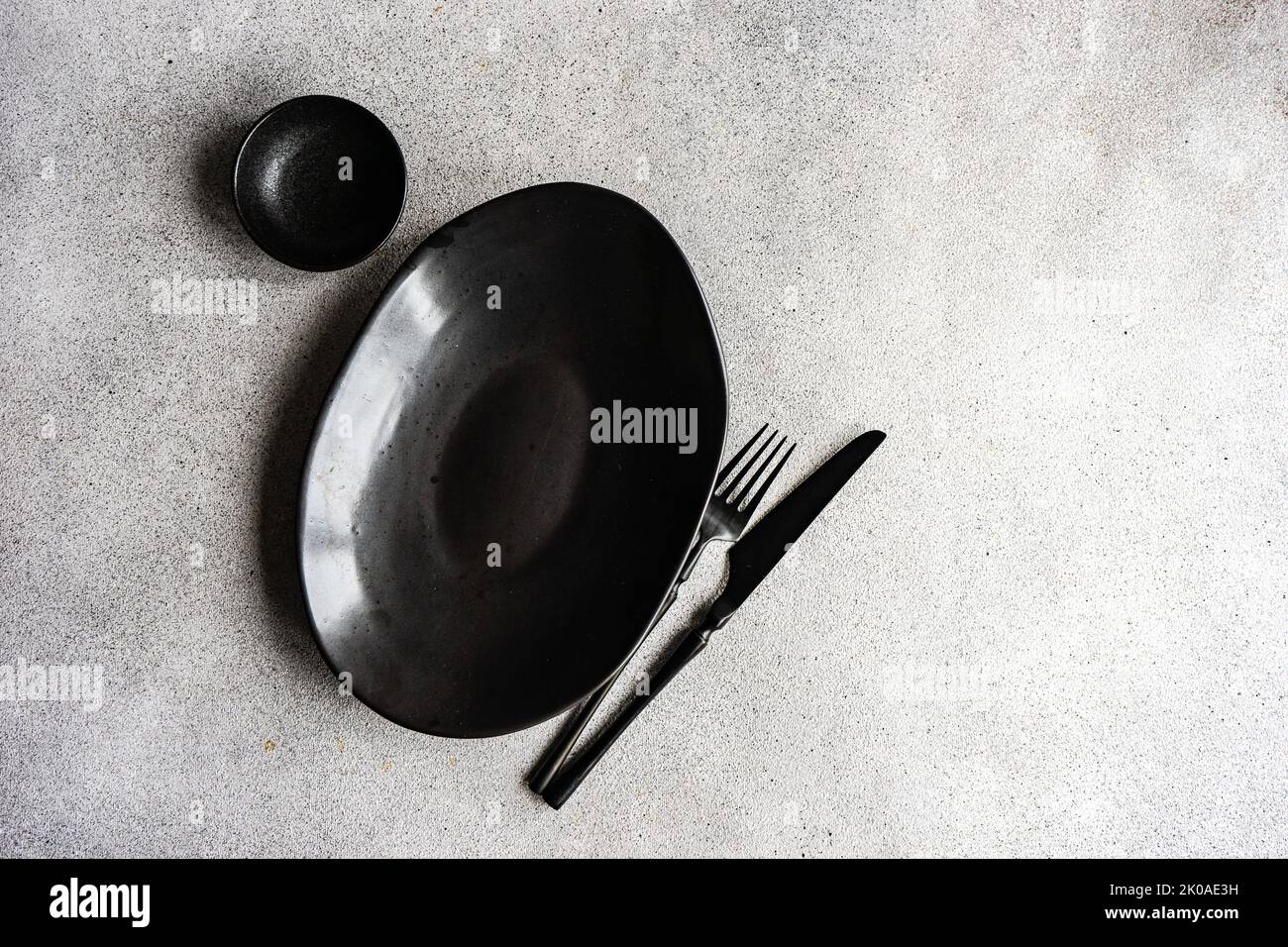 Minimalistic table setting with ceramic bowl and cutlery on concrete ...