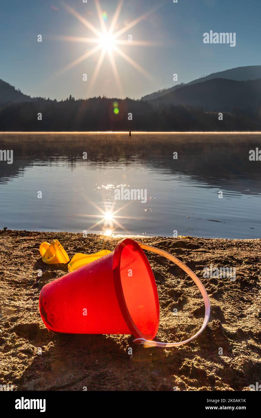 Early morning sunburst with an orange childs bucket in foreground on ...