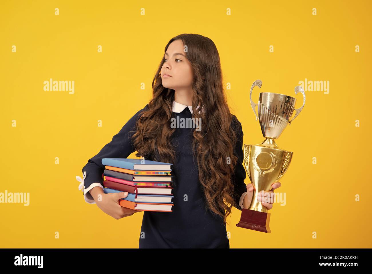 Schoolgirl in school uniform celebrating victory with trophy. Teen ...