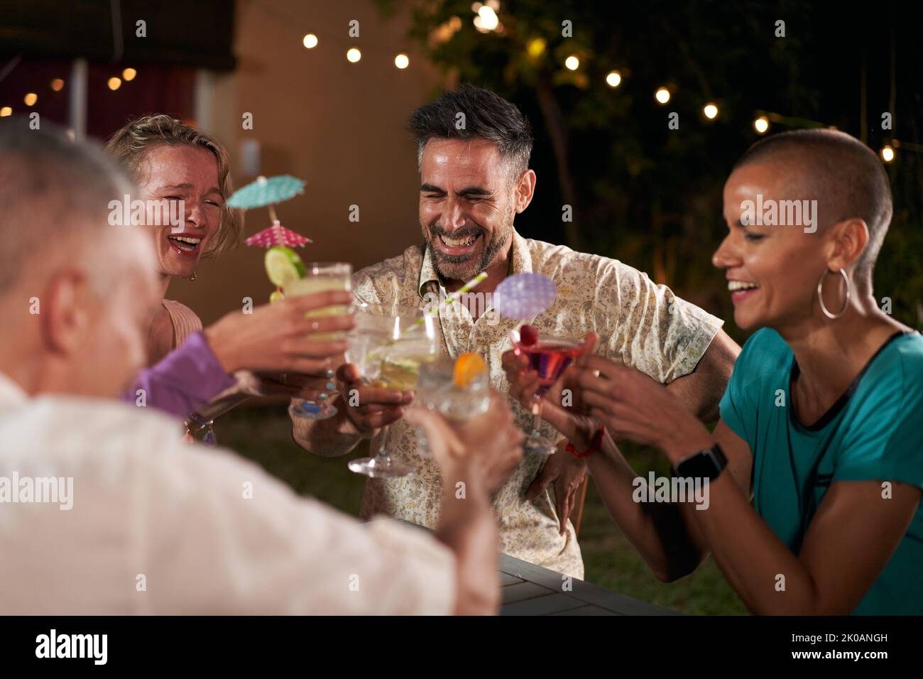 Group of merry friends at an evening party toasting with cocktails and ...