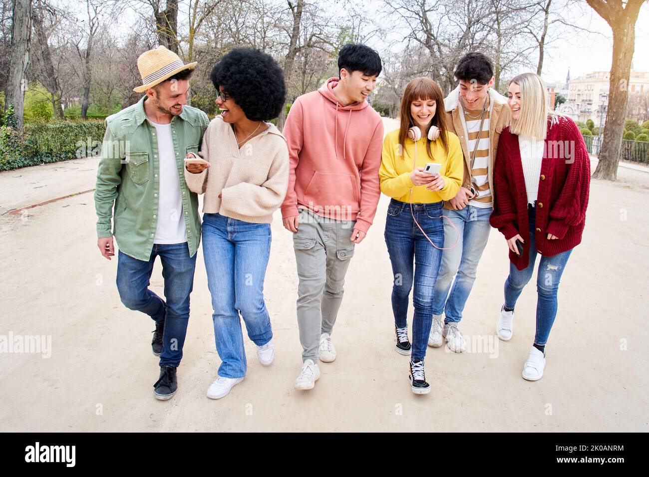 Group Of Young Multiracial Friends Using Mobile Phones And Walking In A