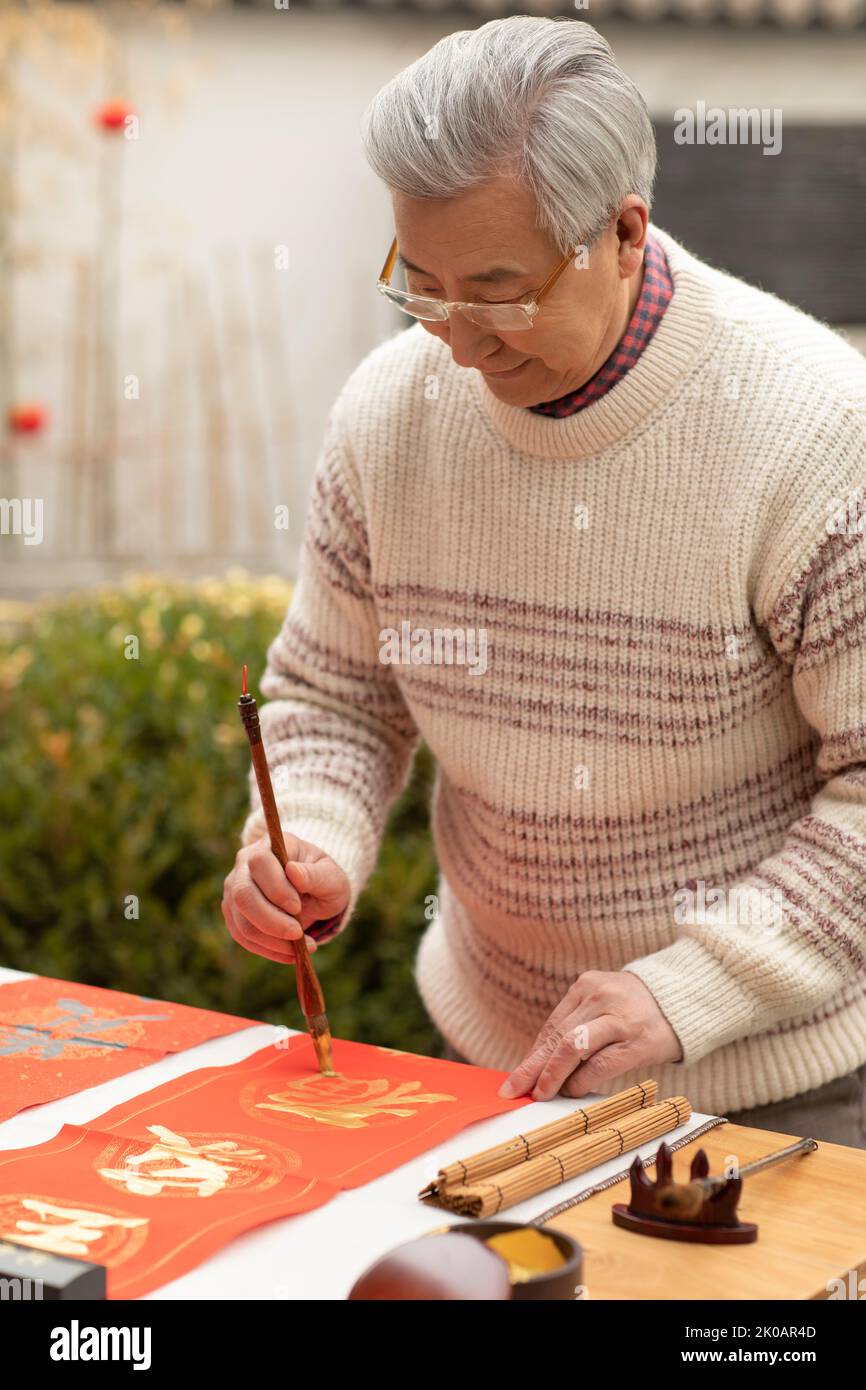 Happy senior Chinese man writing calligraphy on couplets Stock Photo ...