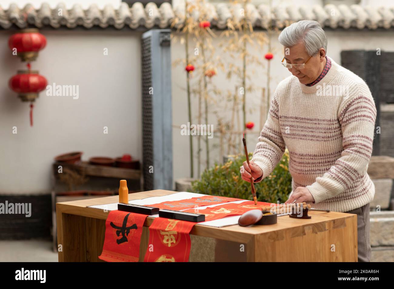 Happy senior Chinese man writing calligraphy on couplets Stock Photo ...