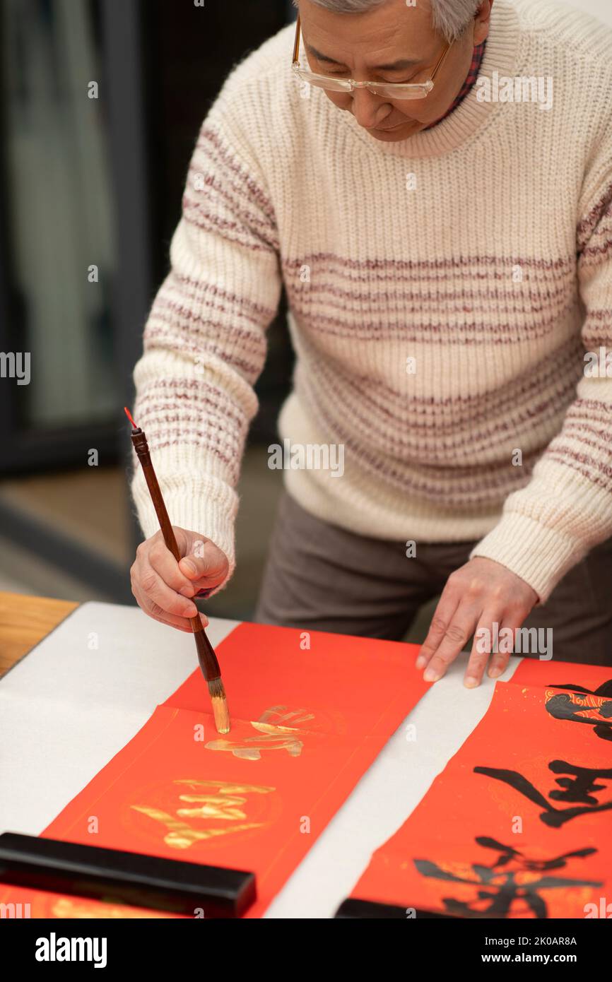 Happy senior Chinese man writing calligraphy on couplets Stock Photo ...