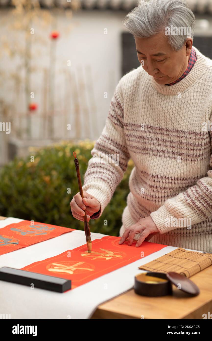 Happy senior Chinese man writing calligraphy on couplets Stock Photo ...