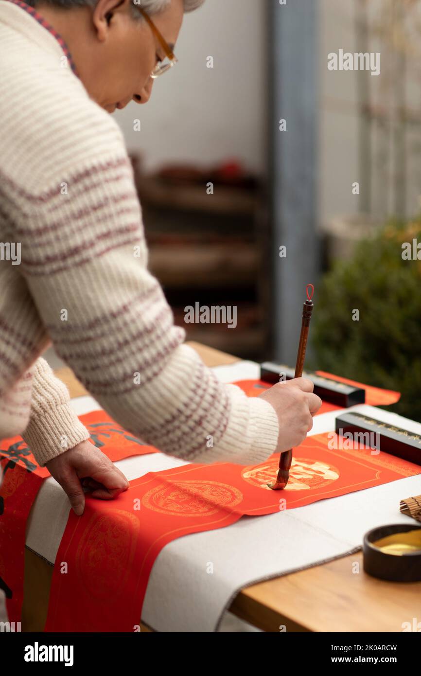 Happy senior Chinese man writing calligraphy on couplets Stock Photo ...