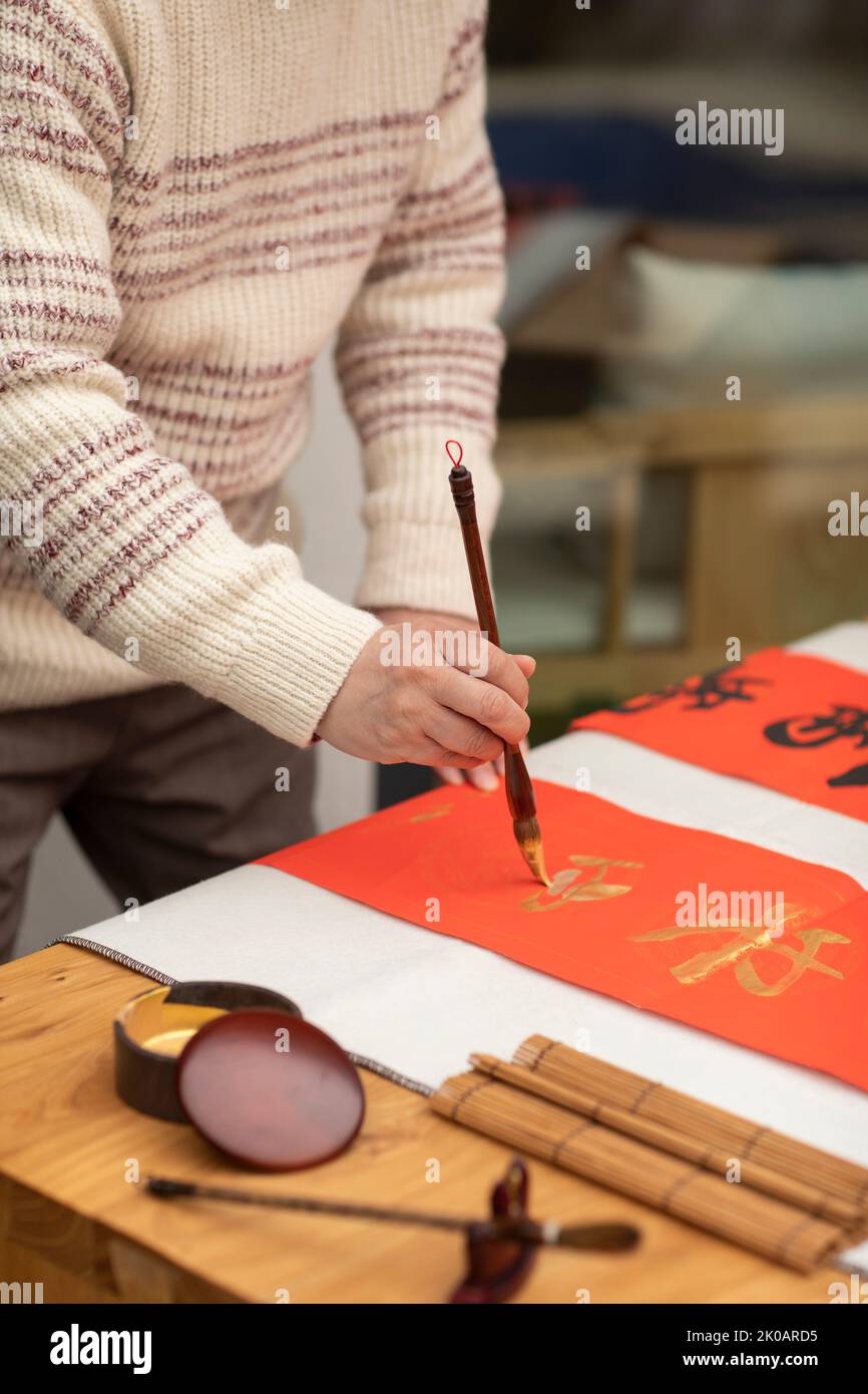 Happy senior Chinese man writing calligraphy on couplets Stock Photo ...