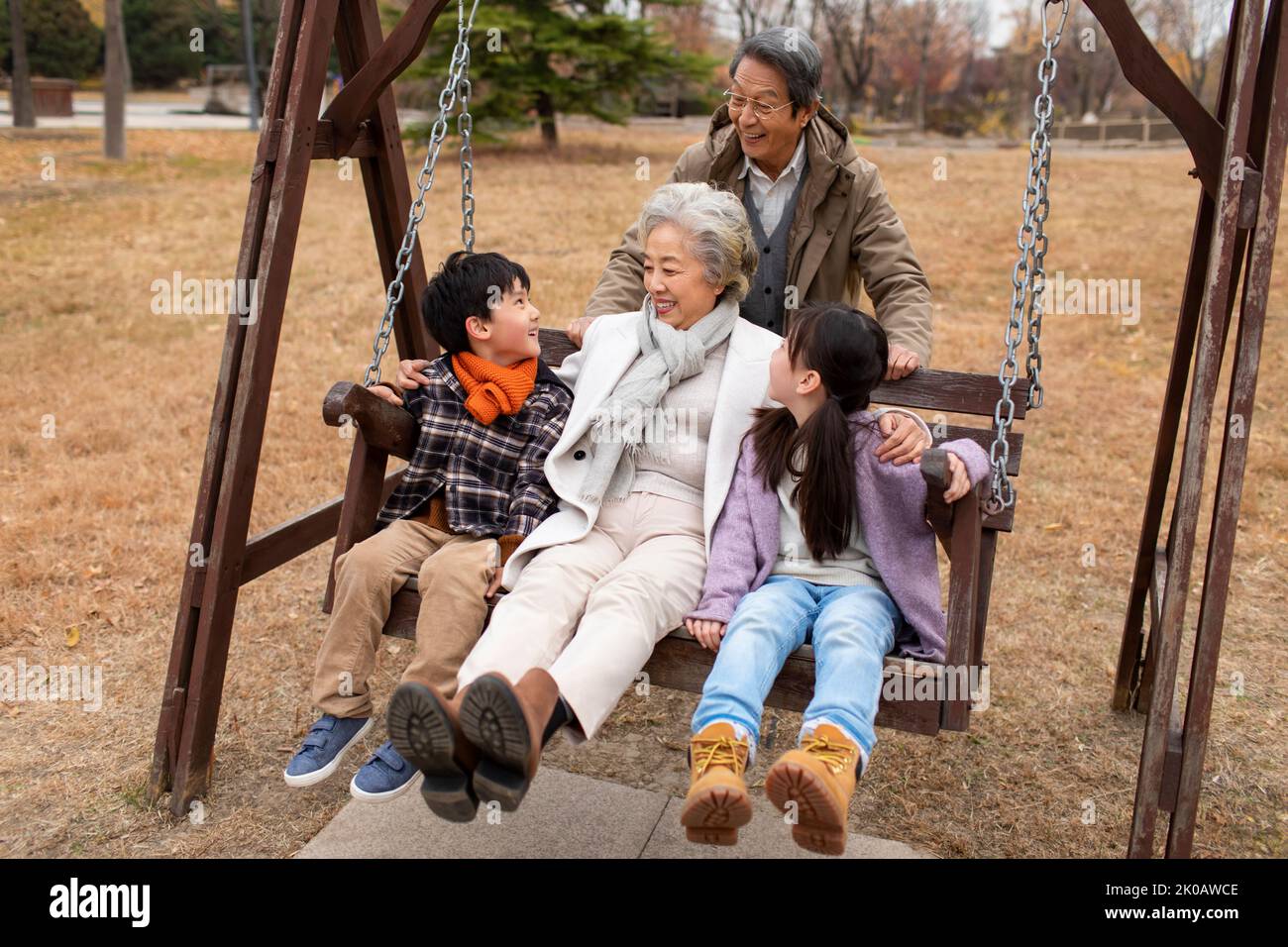 Happy Chinese family playing on a swing Stock Photo - Alamy