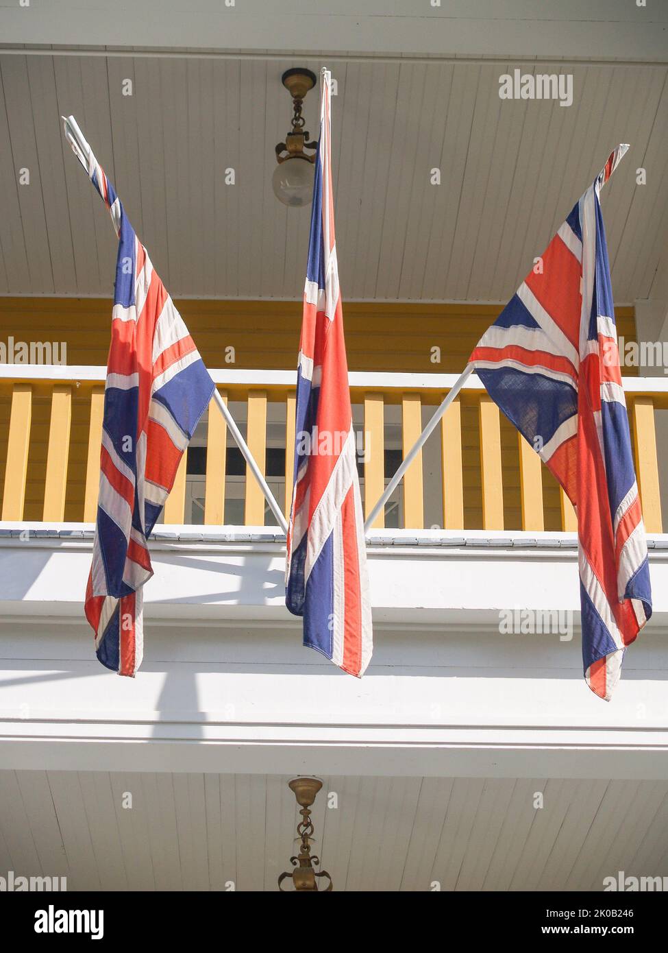 Three Union Jack flags on poles on exterior of colonial style building ...