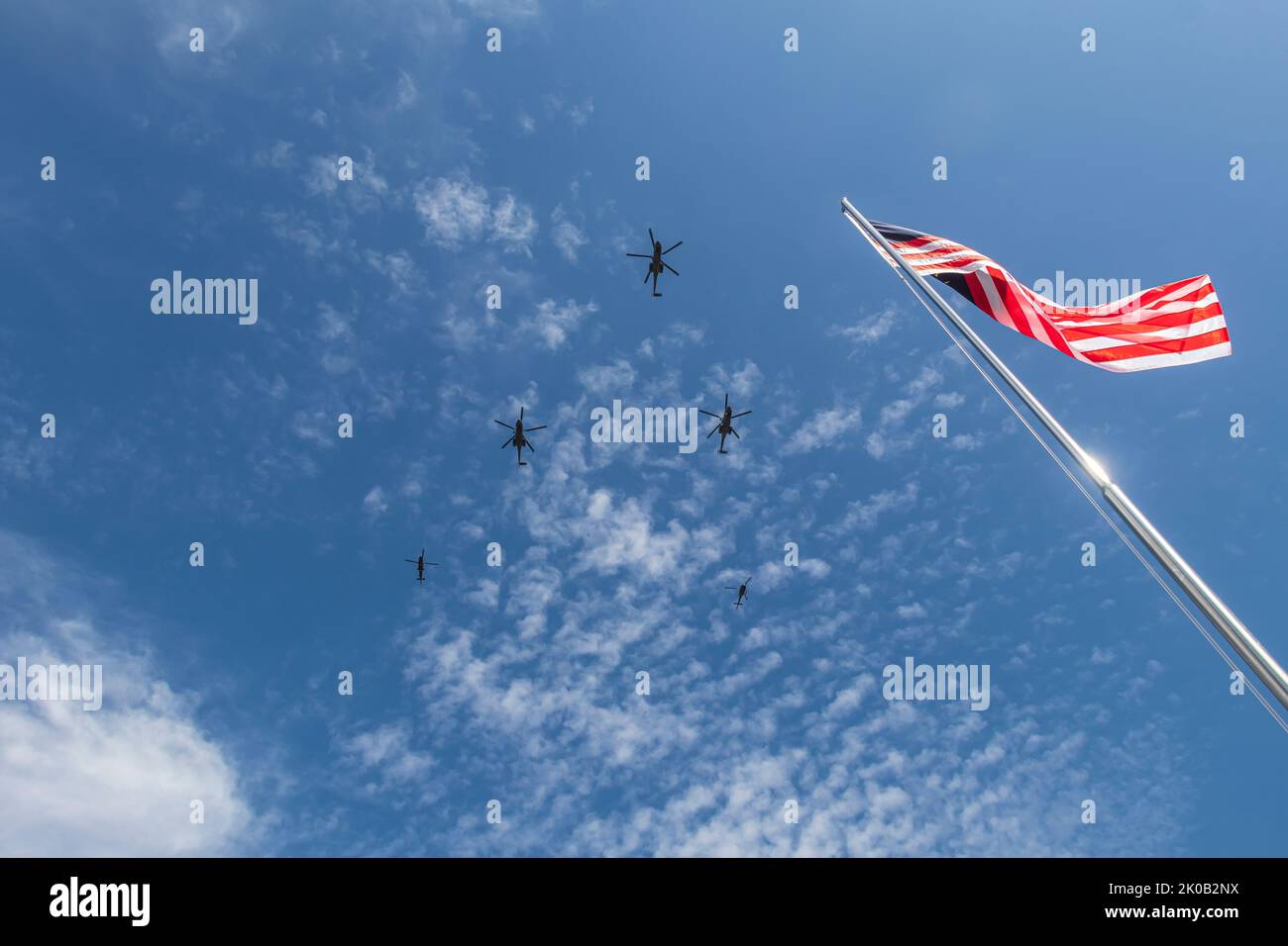 Silhouette of helicopters flying in formation above a flagpole with ...