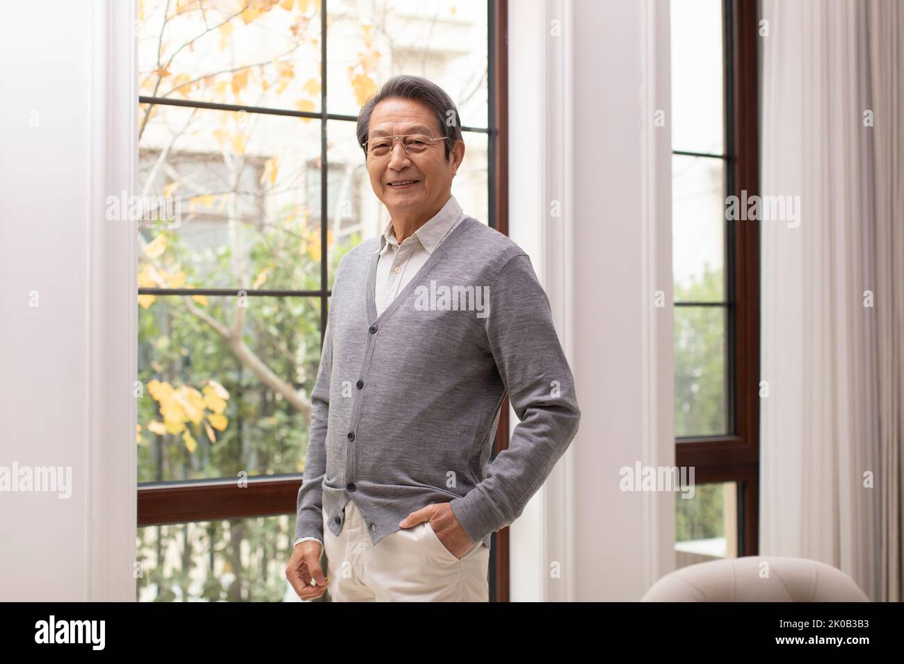 Senior Chinese man standing in front of window Stock Photo - Alamy