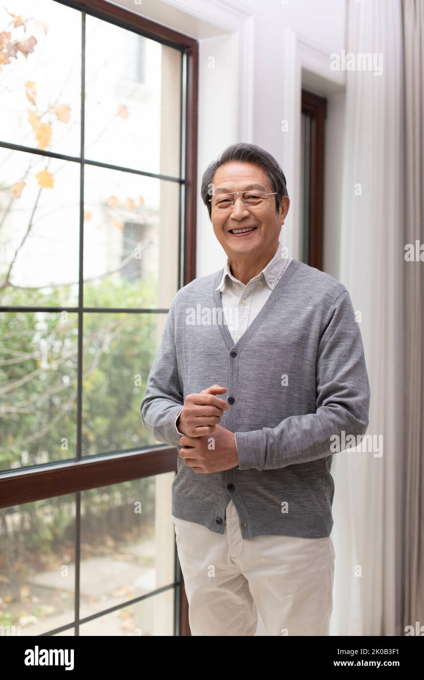 Senior Chinese man standing in front of window Stock Photo - Alamy