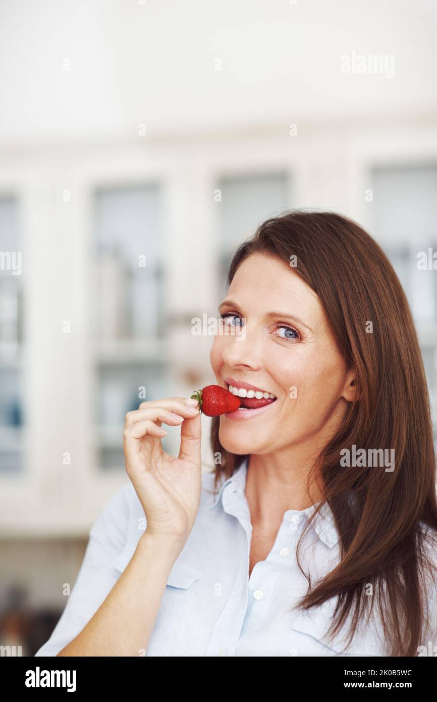 Bite-sized Bliss. An attractive brunette eating a strawberry while ...