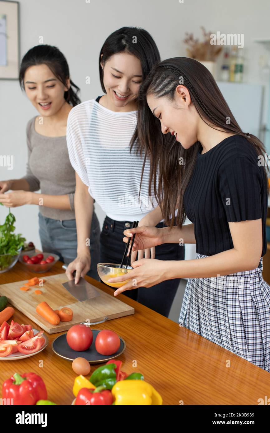 Young Chinese friends cooking in kitchen Stock Photo - Alamy