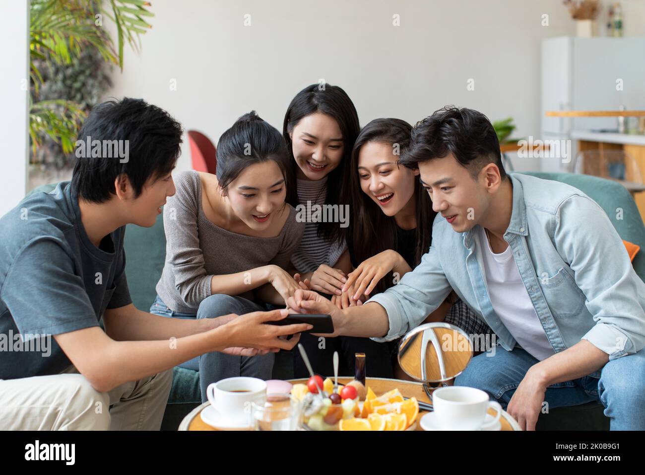 Young Chinese friends using smart phones on sofa Stock Photo - Alamy