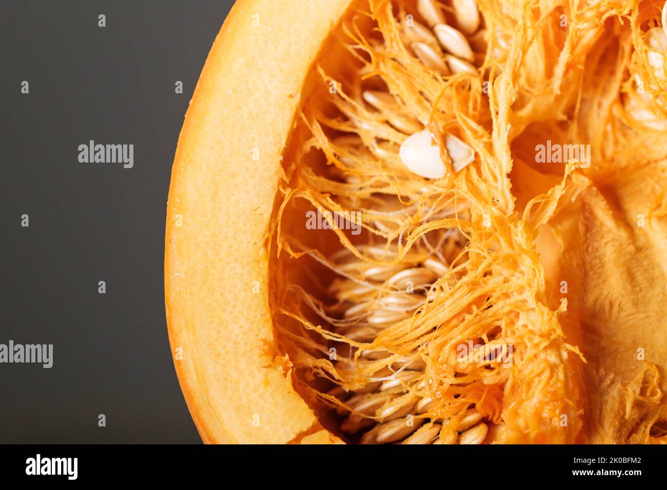 Cut in half Halloween pumpkin showing pulp full of ripe seeds. Close-up ...