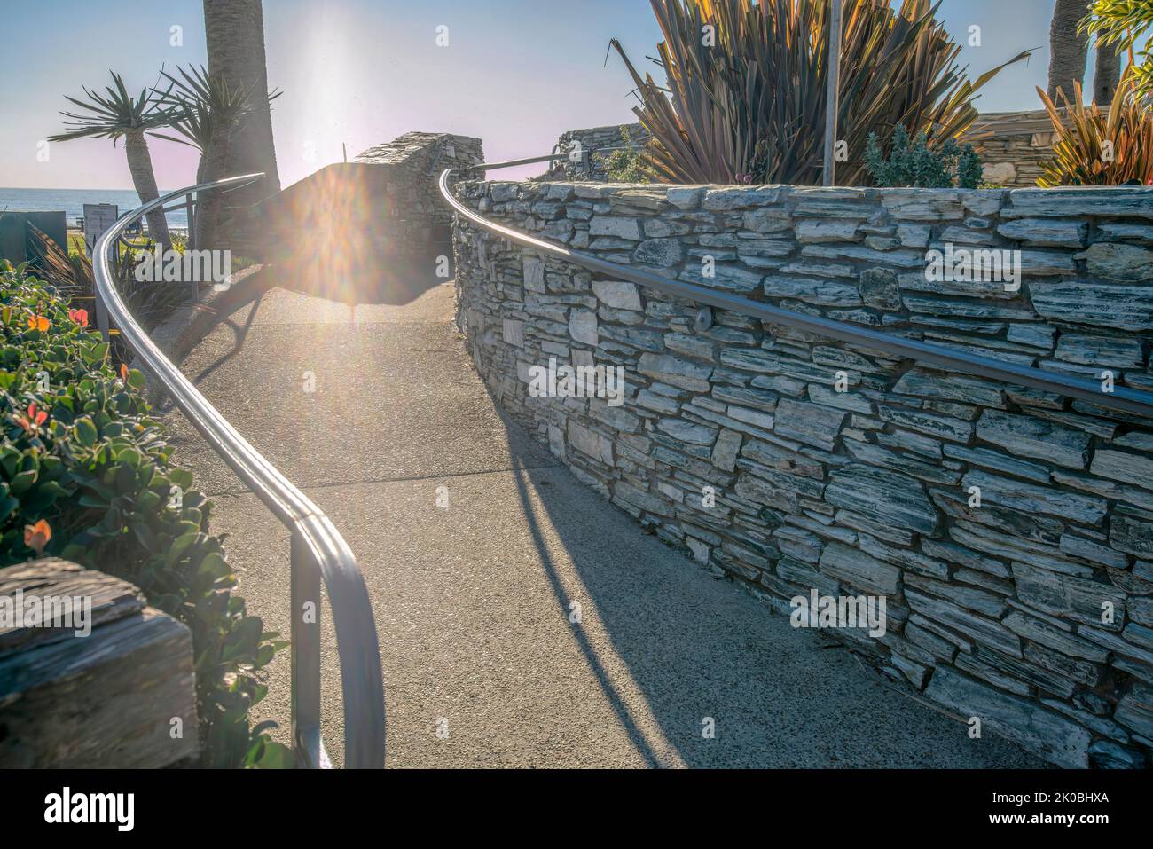 La Jolla, California- Concrete walkway with stone walls and metal bar ...