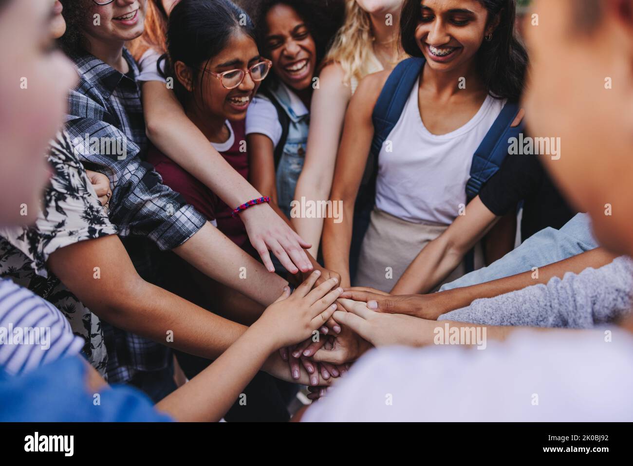 Group of multicultural teenagers smiling happily while putting their ... Group of multicultural teenagers smiling happily while putting their ...