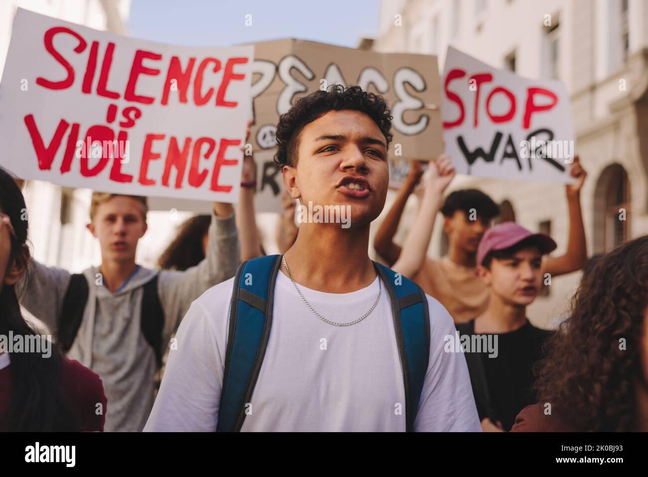 Teenage boy shouting slogans while marching against war and violence ...