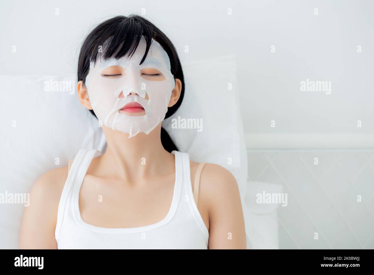 Beautiful young asian woman with sheet facial mask and sleep on bed at ...