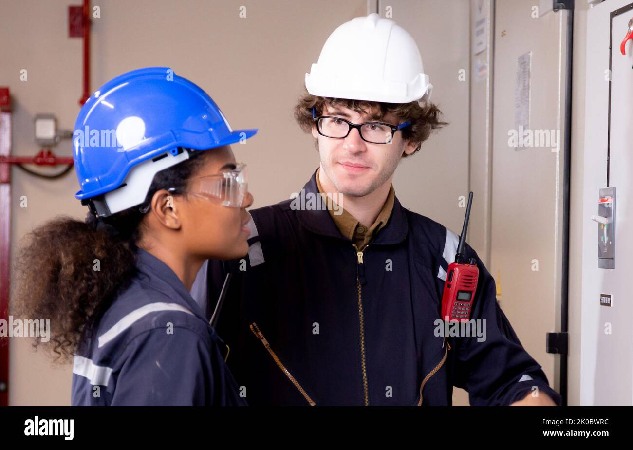 Electrical young woman and man engineer examining maintenance cabinet ...
