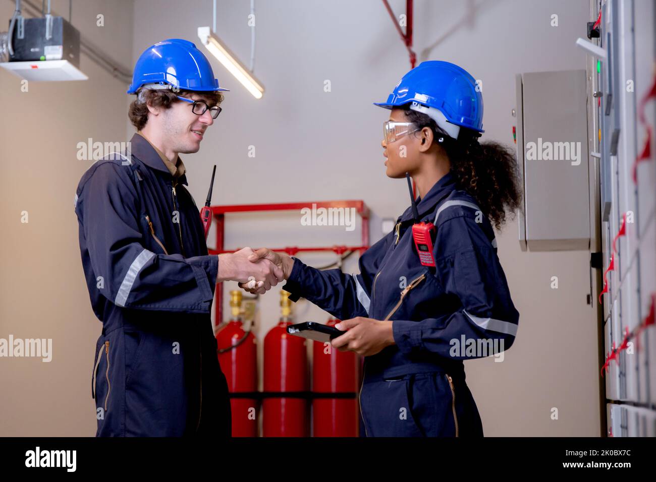Electrical young woman and man engineer examining maintenance cabinet system electric and ...