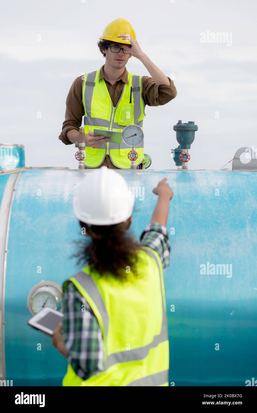 Young woman and man engineer examining pipeline and talking in the ...