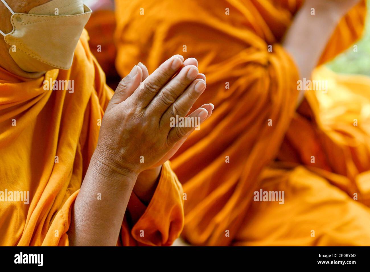 A close up view of a Thai monk's wai, the clasping of hands in prayer ...